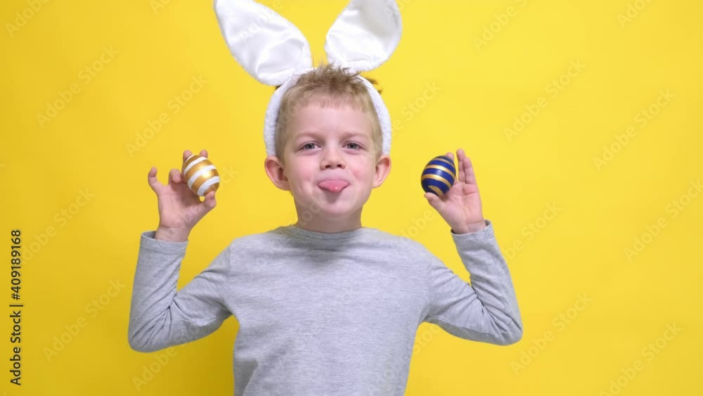 Portrait Easter kid. Boy in rabbit bunny ears on head having fun looking into the camera sticks ...