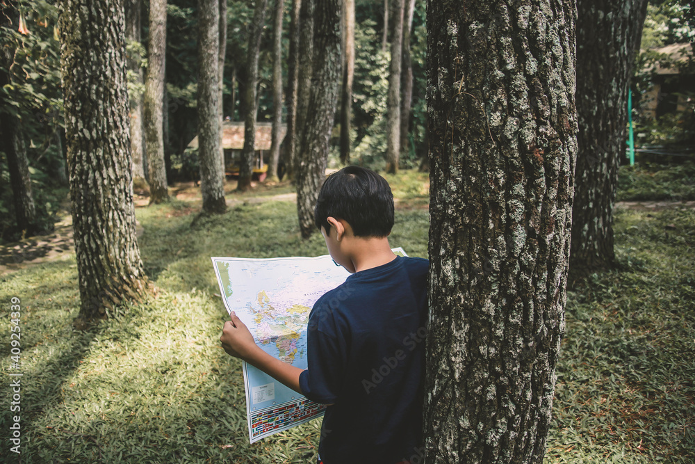 Serious boy looking for route on the jungle using map for navigation ...