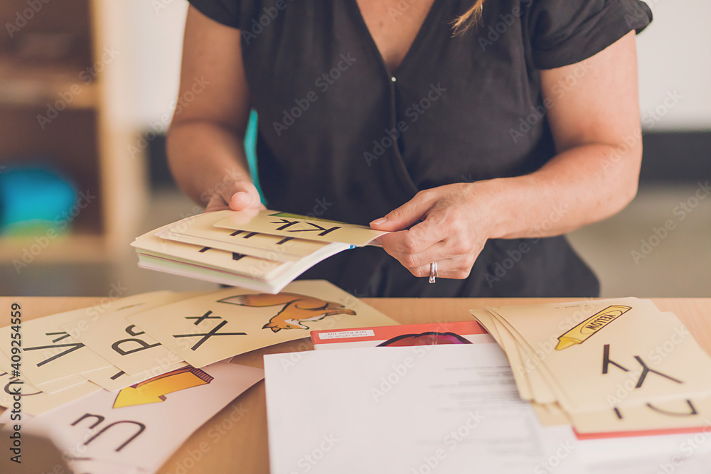Female teacher sorting out alphabet picture cards in her classroom ...