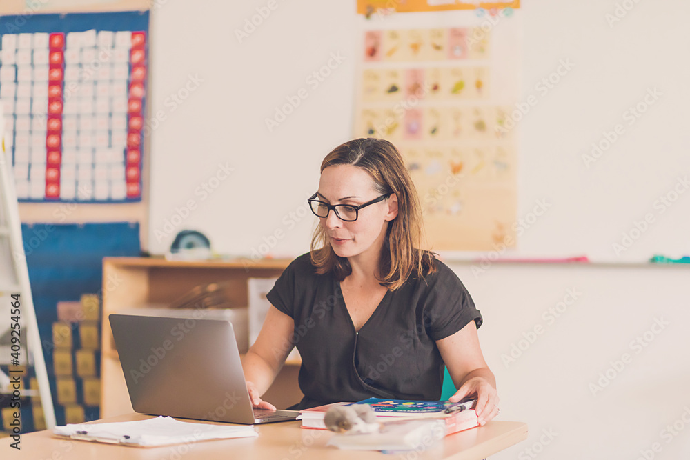 Female teacher typing on her laptop in her classroom. Stock Photo ...