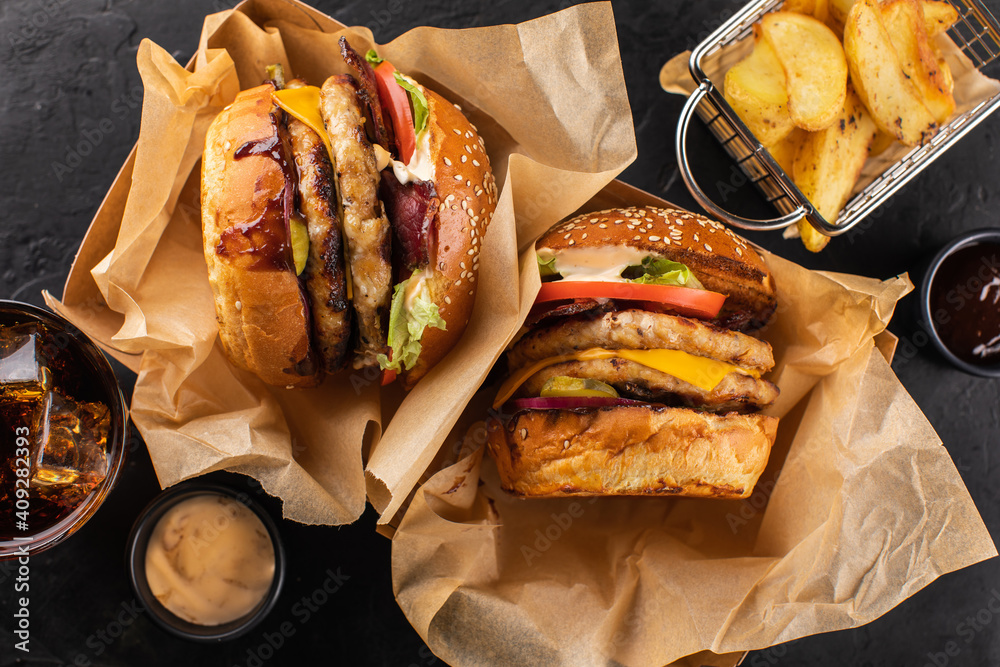 Two yummy grilled chicken burgers in a craft box, fries and cola on a ...