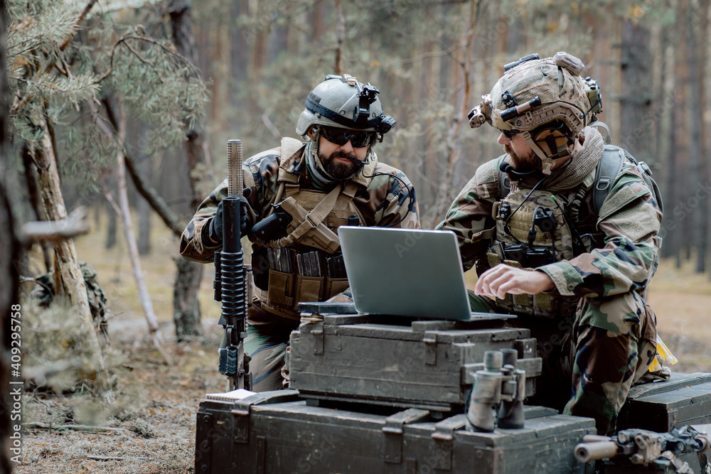 Bearded soldiers in uniform sit on military transport crates, analyze ...