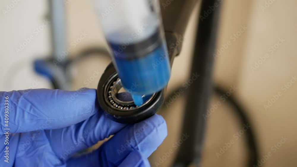 the mechanic lubricates the bearing from a syringe, bycicle service ...