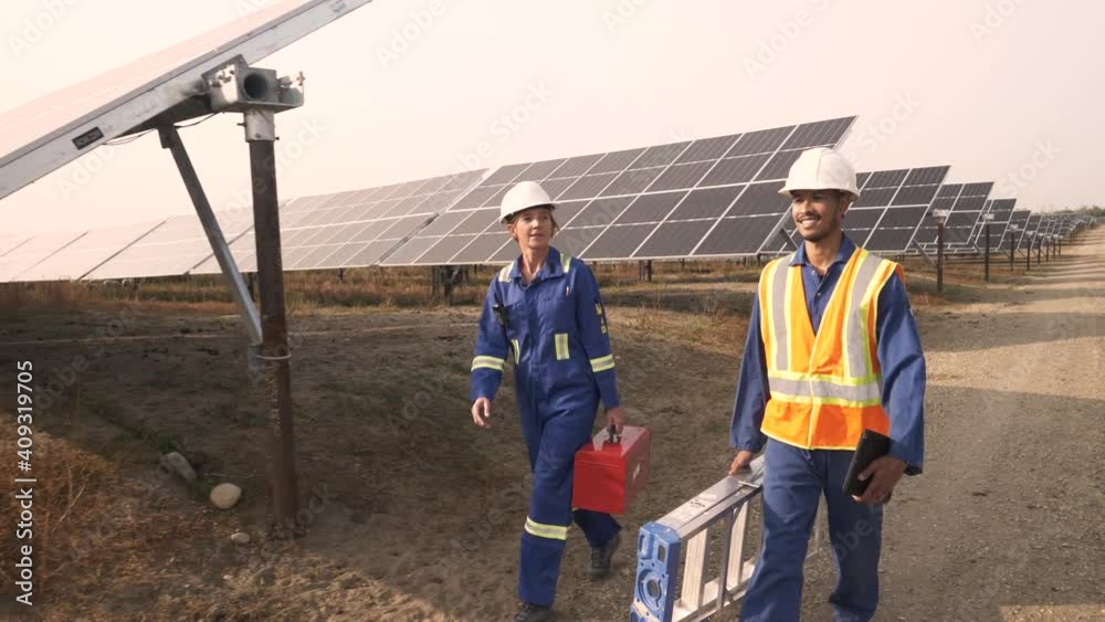 Slow motion of technicians carrying ladder and toolbox in solar farm ...