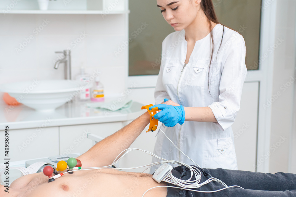 Cardiogram of the heart. Cardiologist attaches electrodes of an ...