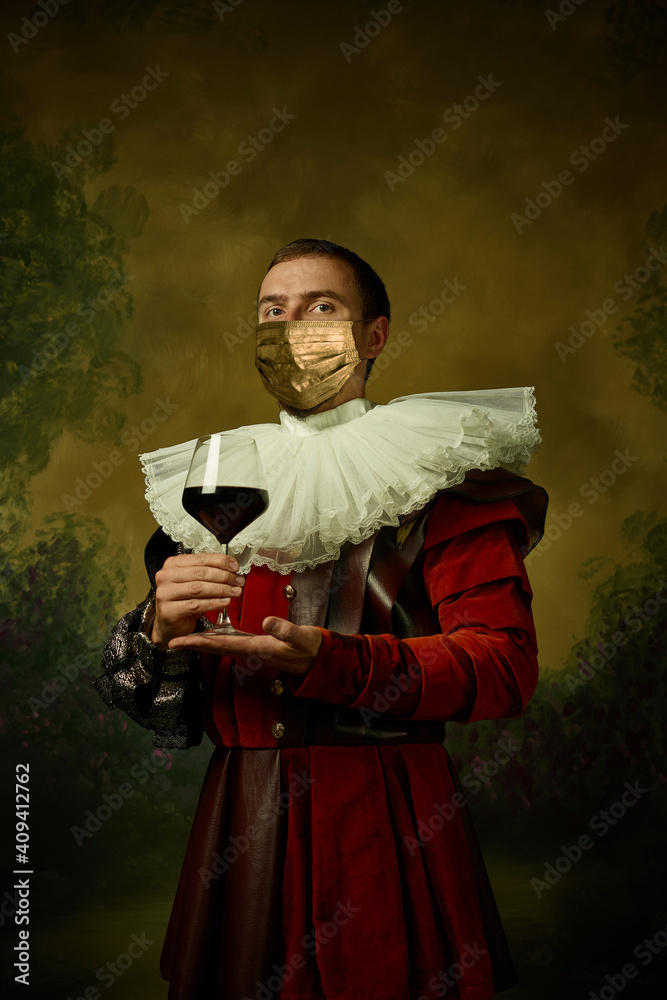 Portrait of medieval young man in vintage clothing and golden face mask ...