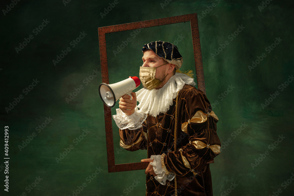 Portrait of medieval young man in vintage clothing, golden face mask ...