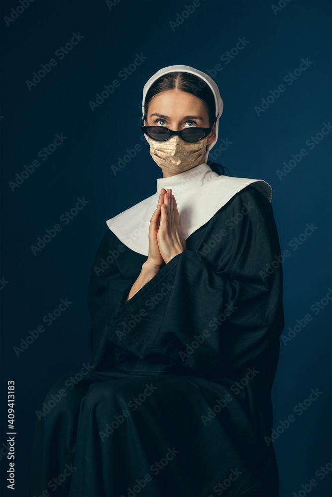 Medieval young woman as a nun in vintage clothing and golden face mask ...