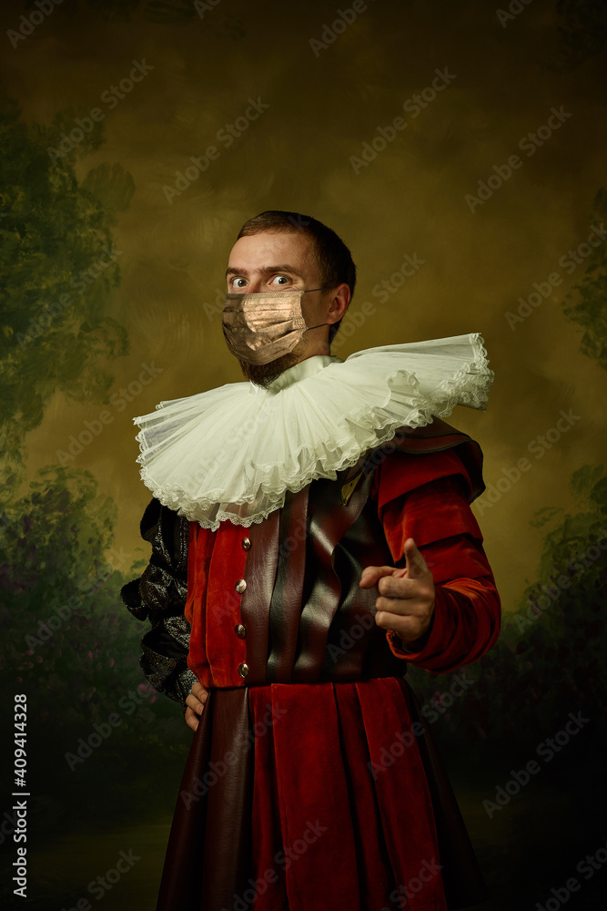 Portrait of medieval young man in vintage clothing and golden face mask ...