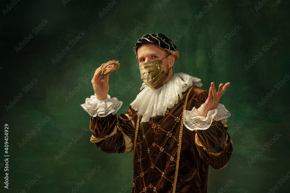 Portrait of medieval young man in vintage clothing, golden face mask ...