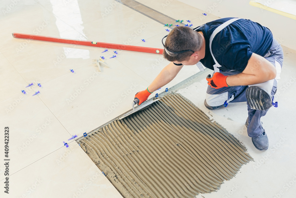 A male construction worker installs a large ceramic tile Stock Photo ...
