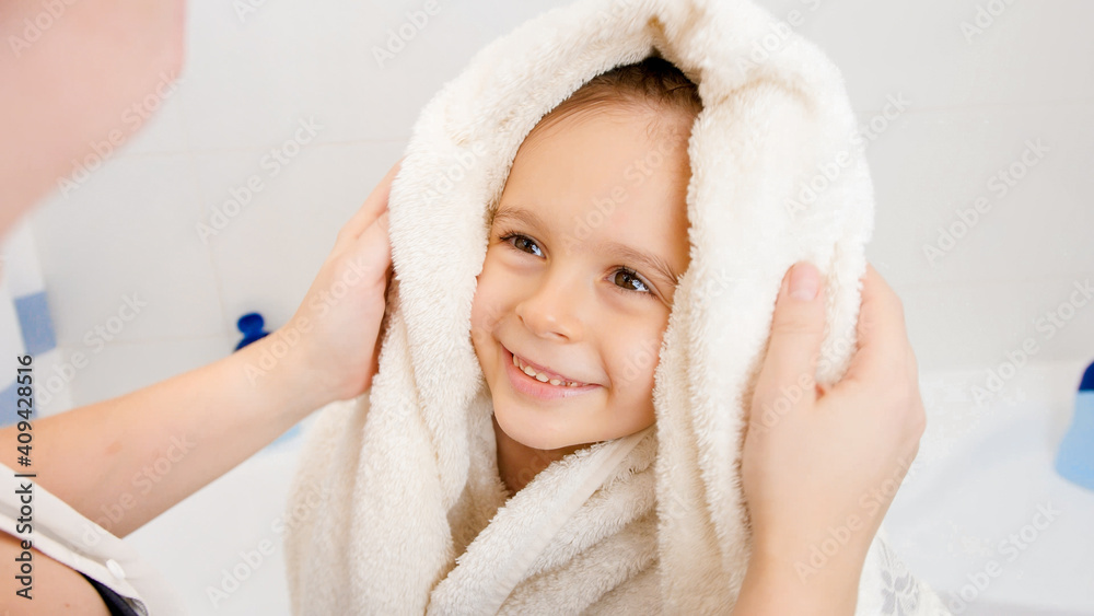 Portrait of cute smiling boy with wet hair wiping and drying with soft ...
