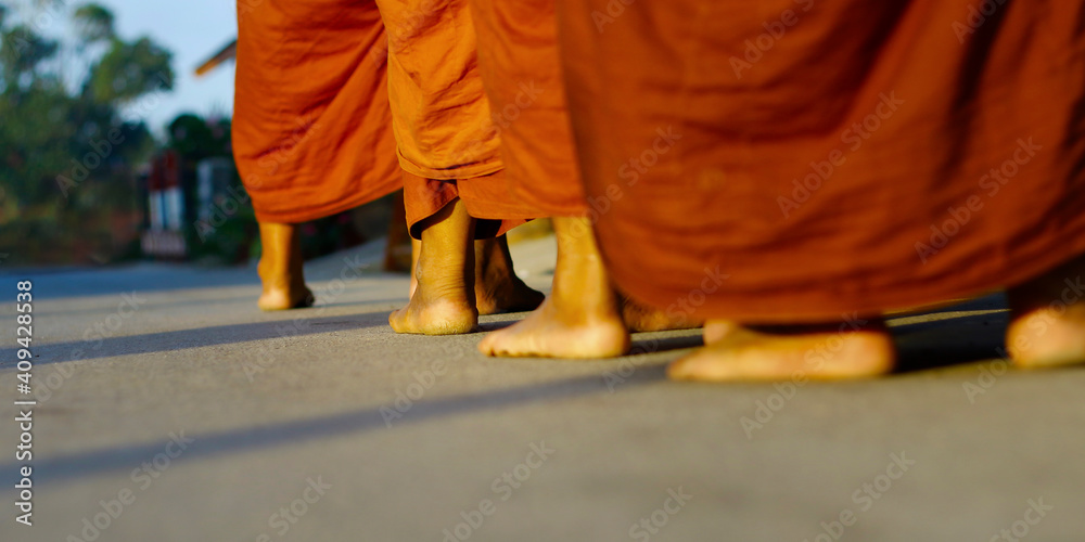 feet of monks dressing orange robe during reception of alms, around ...