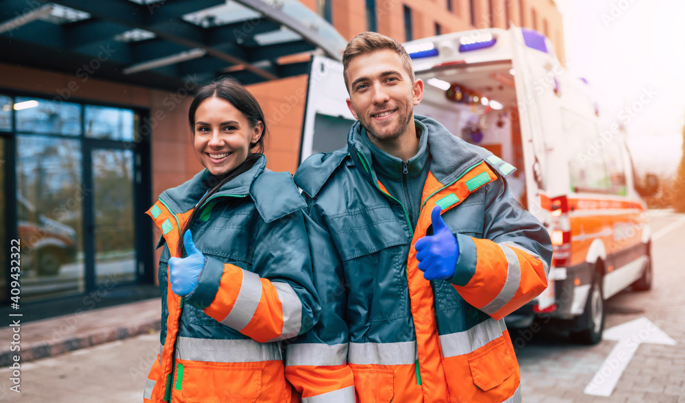 Two confident young doctors looking on the camera on ambulance and ...