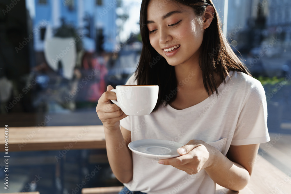Beautiful asian girl drinking coffee in cafe by the window, looking at ...
