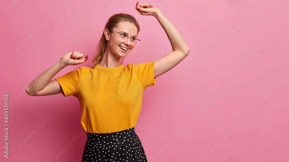 Positive millennial girl dances carefree against pink studio background ...