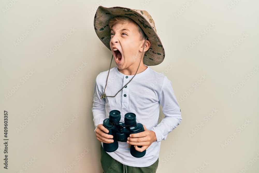 Little caucasian boy kid wearing explorer hat holding binoculars angry ...