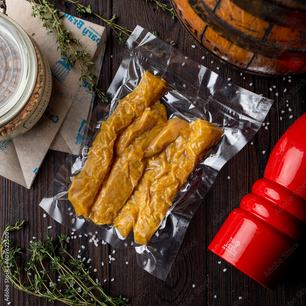 Premade frozen chicken sticks in a vacuum package on wooden table, top ...