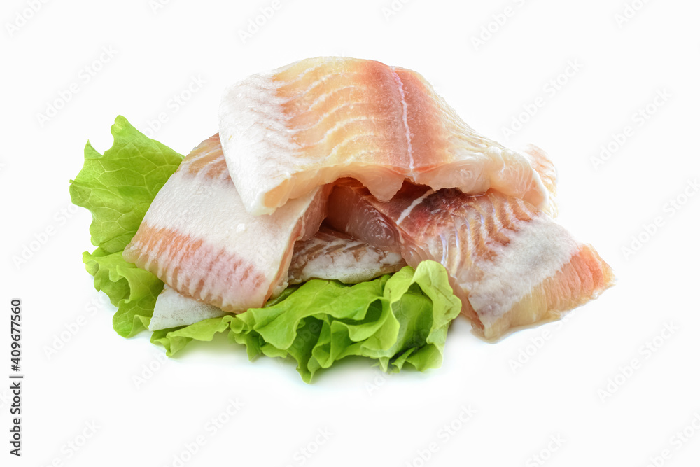 Pangasius fish fillet, pieces on a green lettuce leaf. Isolated on a ...