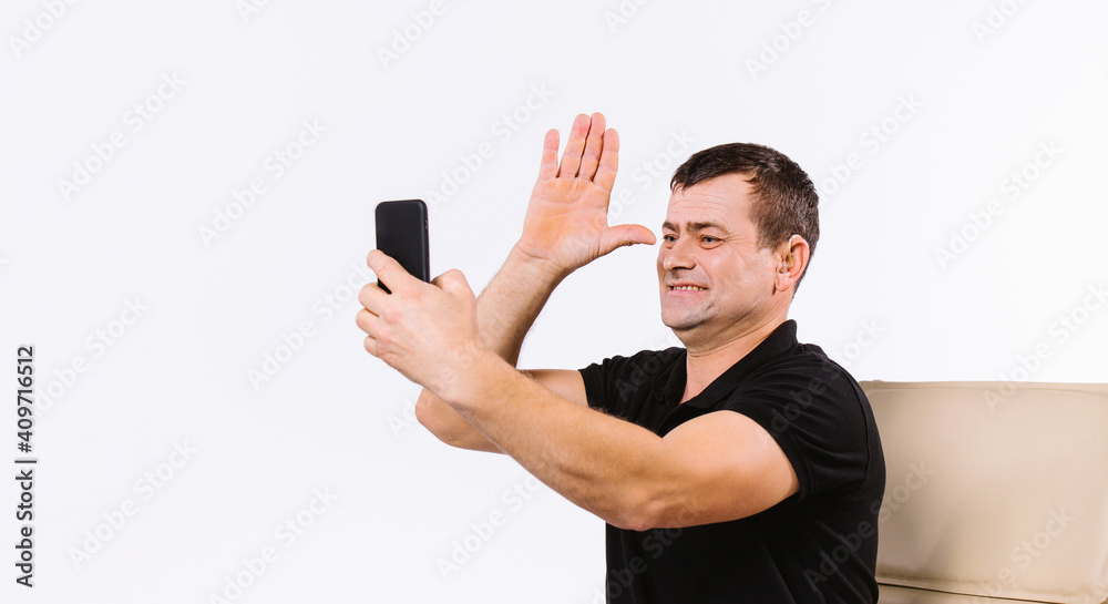Smiling man sitting in a chair communicates by video using gestures and ...