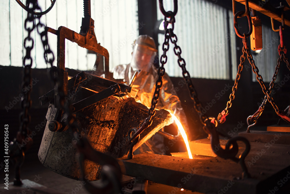 Worker in foundry pouring hot metal into mold. Molten iron casting ...