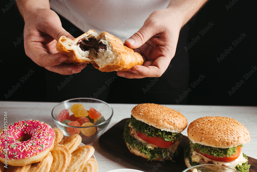 Unhealthy snack, junk food, compulsive overeating. Young overweight man ...