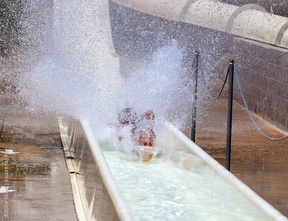People having fun at waterpark. There are legs of man sliding down ...