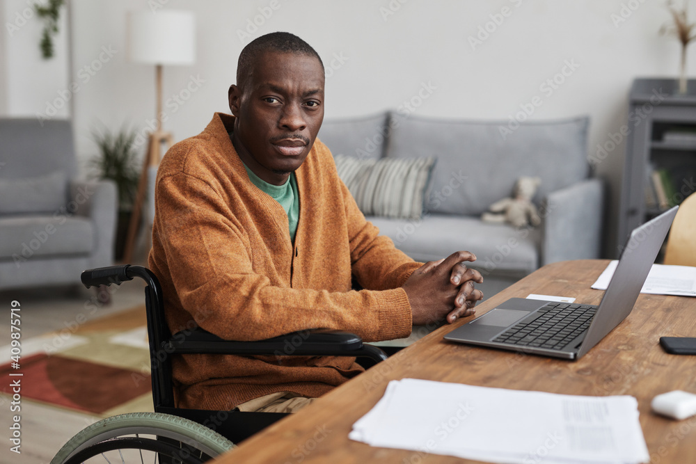 Portrait of adult African-American man using wheelchair while working ...