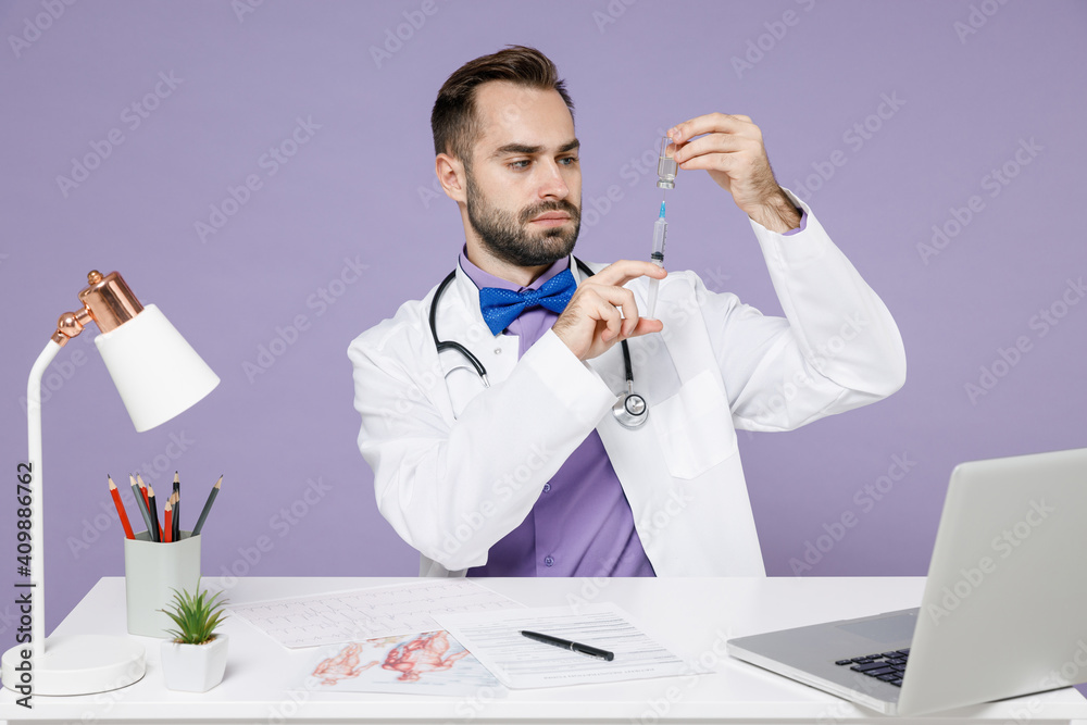 Confident nurse male doctor man in white medical gown suit sits at desk ...