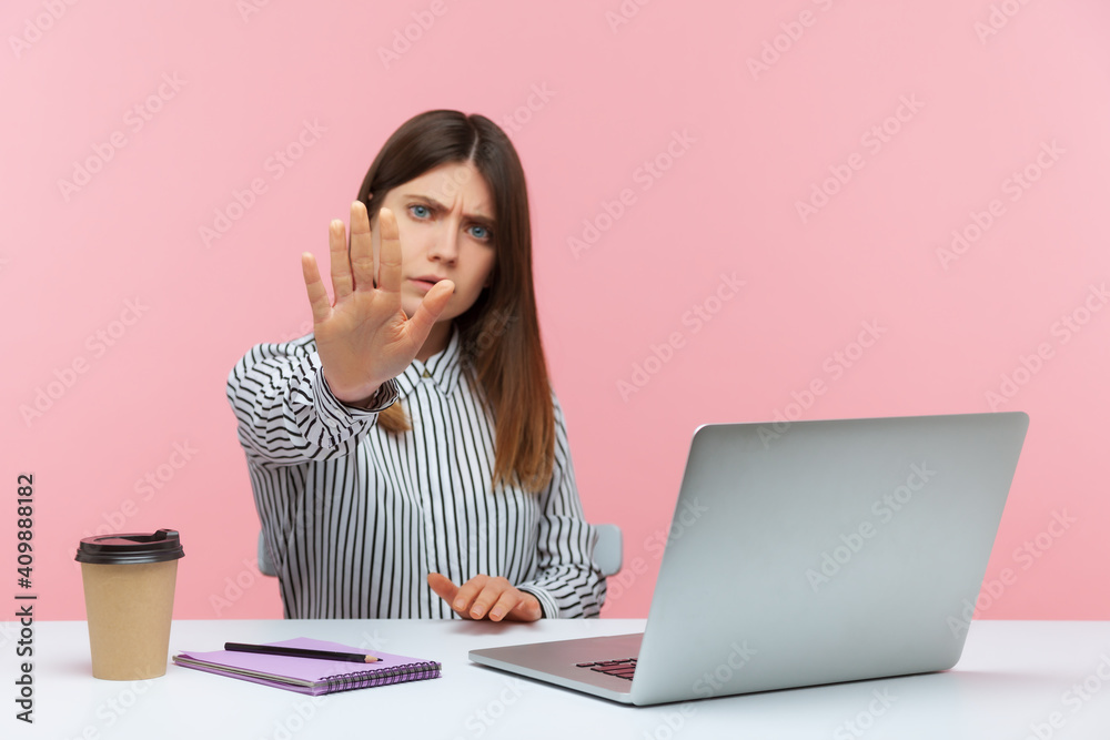 Serious confident business woman in striped shirt holding stop gesture ...