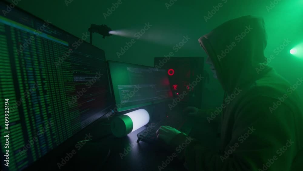 Anonymous person in a white mask works on the computer, inputs code ...