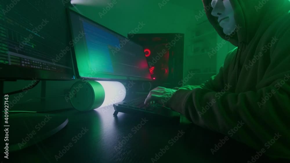 Anonymous person in a white mask works on the computer, inputs code ...