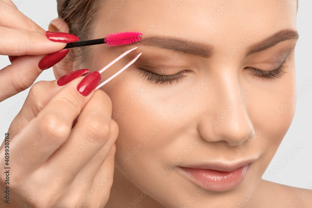 Foto de Makeup artist combs and plucks eyebrows after dyeing in a ...
