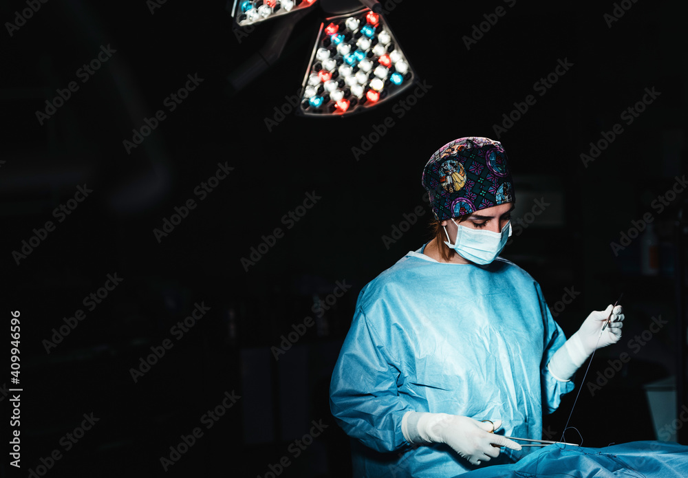 Side view of focused professional female surgeon with surgical tools ...