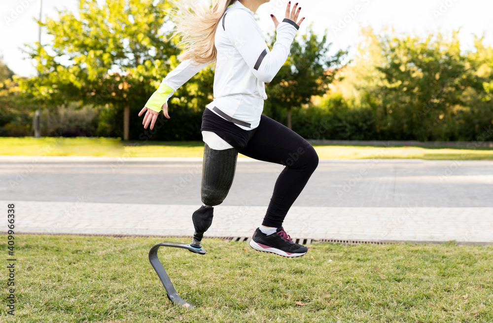 Side view of Paralympic female runner with artificial leg doing ...