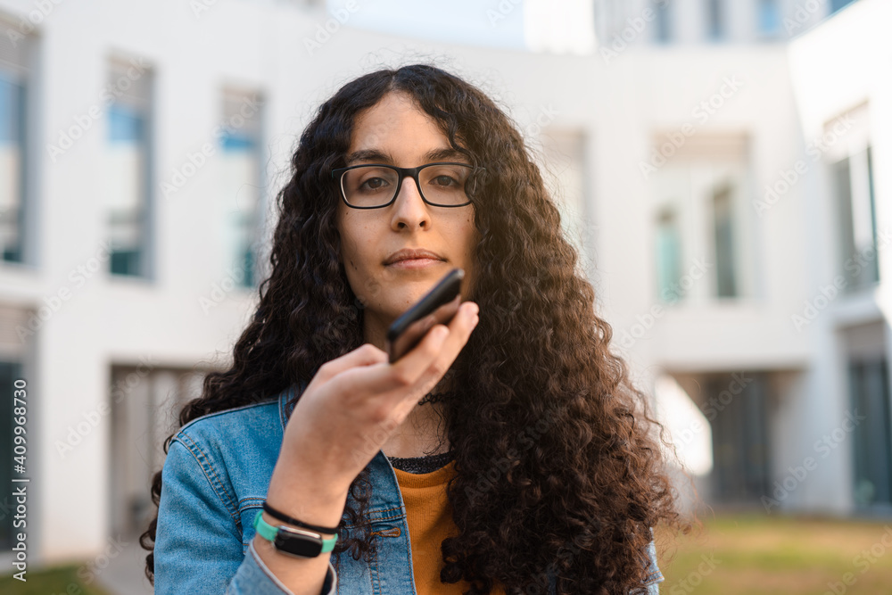 Transgender woman sending a voice message with her cell phone looking ...
