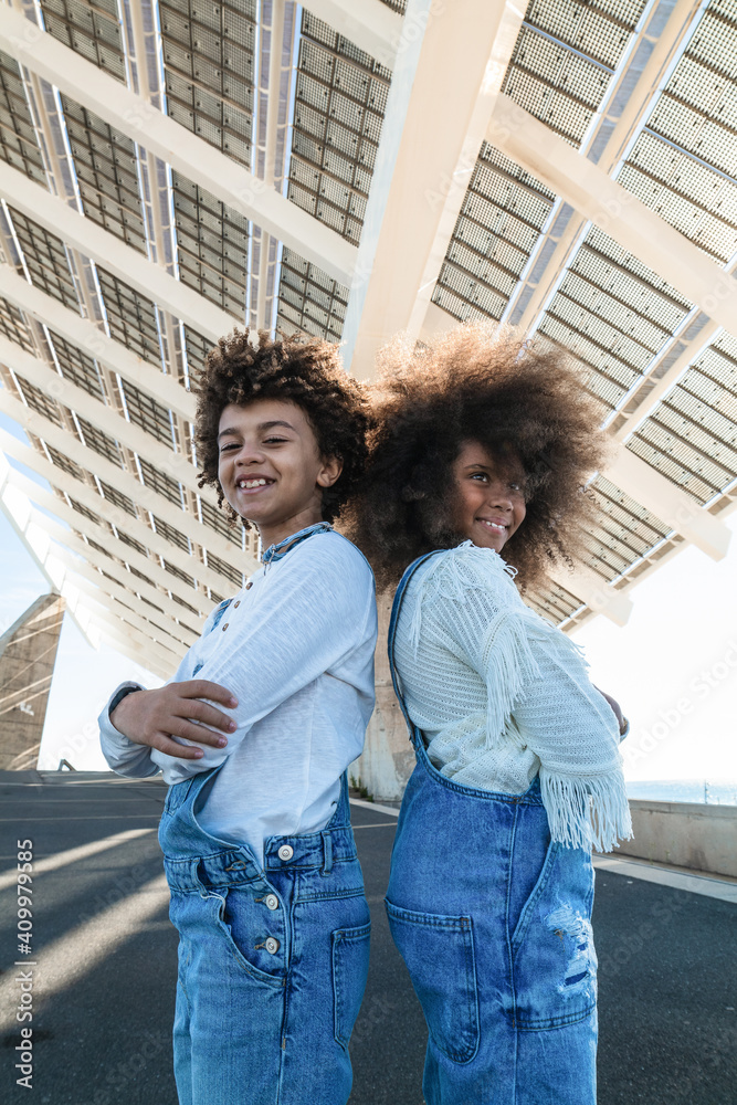 Low angle side view of smiling teen black sister and brother with Afro ...