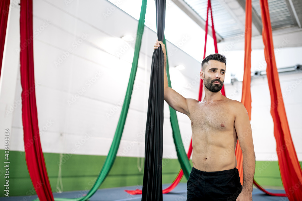 Crop muscular man grasping piece of black aerial silk during dance ...