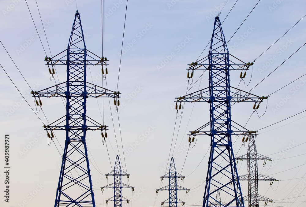 High voltage power lines pylons and electrical cables on a clear blue ...