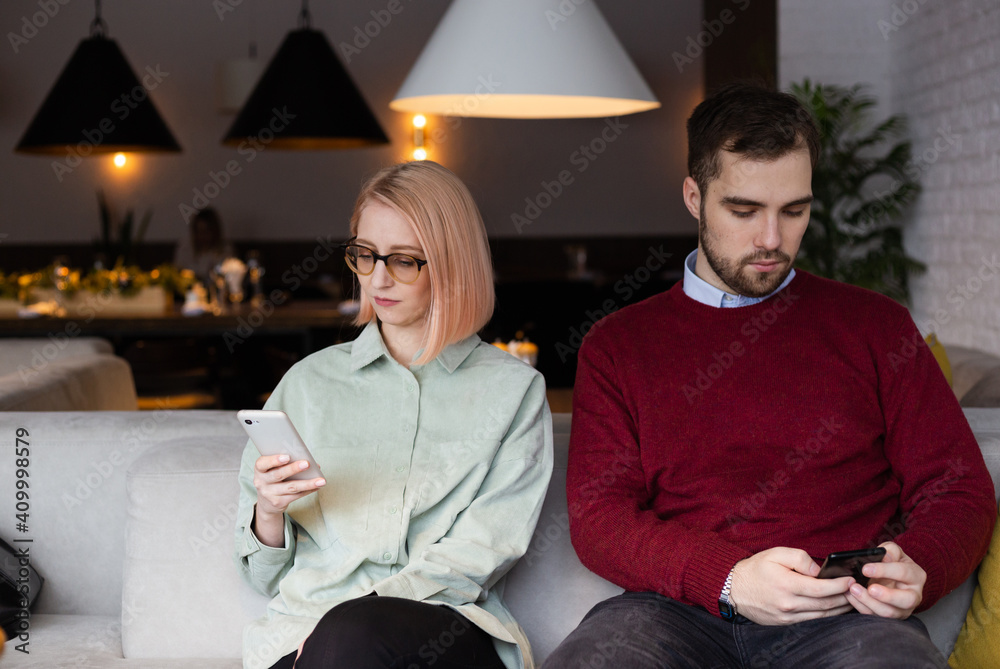 Smartphone addiction and phubbing concept. Young couple on boring date ...