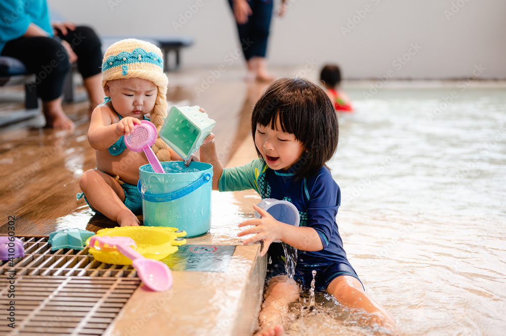 Happy child boy and little girl playing toy in swimming pool.Having fun ...