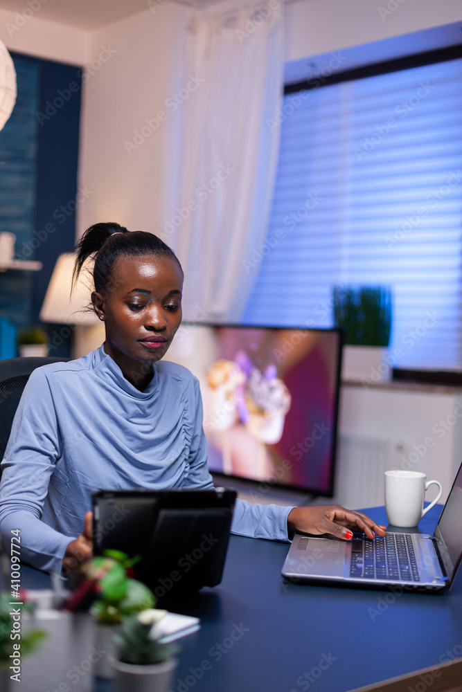 African freelancer using tablet pc working from home working late at ...