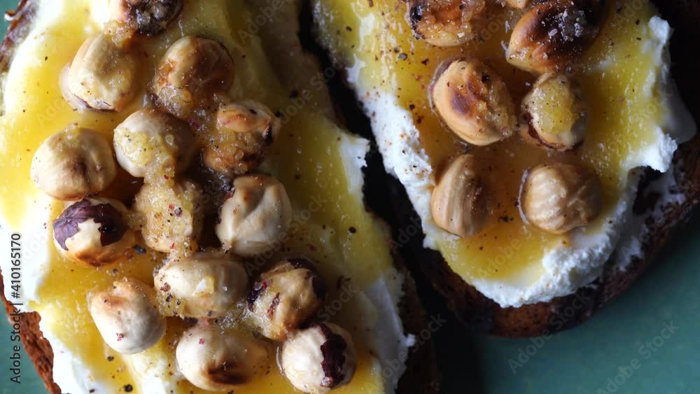 Two bread toast with cream cheese, roasted hazelnuts, honey, pepper and ...