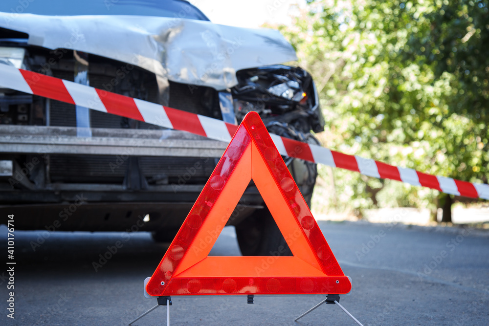 Red emergency triangle and Red warning police tape afore Destroyed car ...