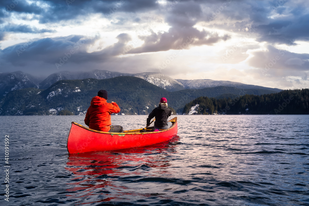 Couple friends on a wooden canoe are paddling in water. Dramatic Sky ...