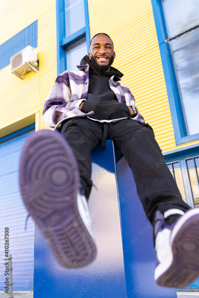 Foto de Happy male rapper with hands in pockets showing sole of shoe ...