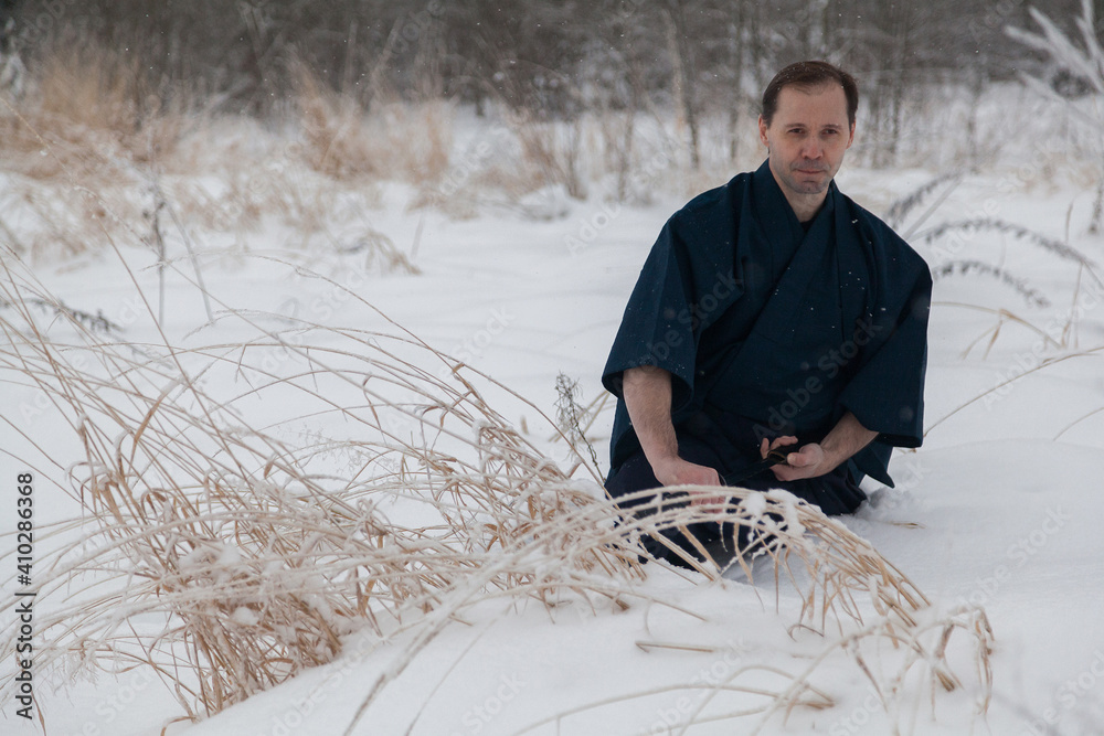 samurai warrior meditates with a sword in the middle of an empty winter ...