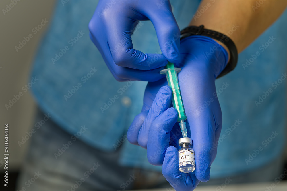 doctor dials the vaccine into a syringe. a nurse with a vaccine and a ...