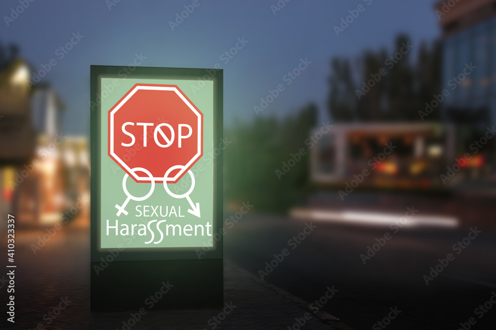 Advertising billboard with text STOP SEXUAL HARASSMENT at night ...