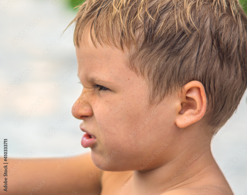 Side portrait mischievous cute blond kid boy, freckled face angry mood ...
